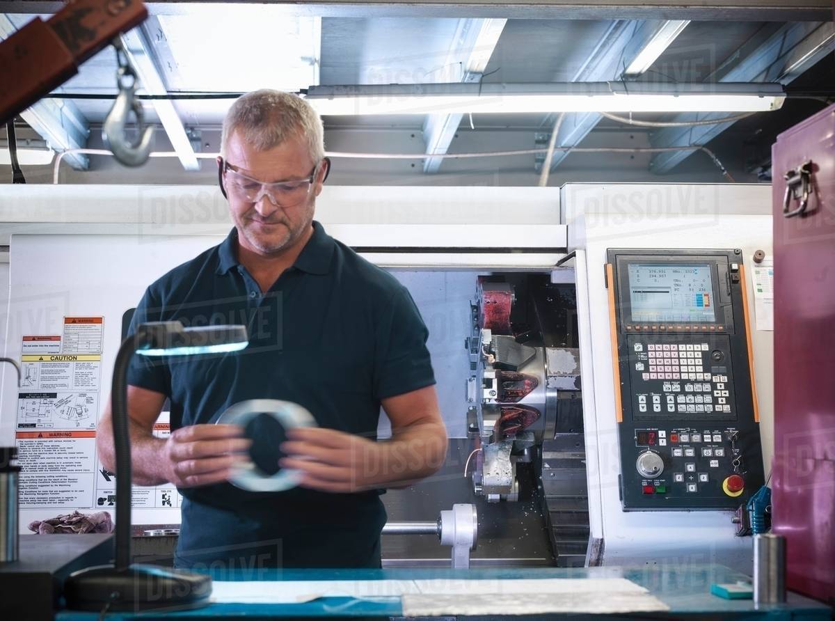 Engineer inspecting metal part in factory - Stock Photo - Dissolve