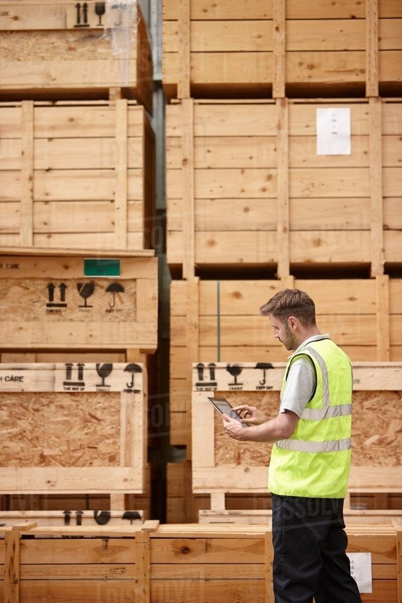 Warehouse worker checking crates in engineering warehouse - Royalty ...