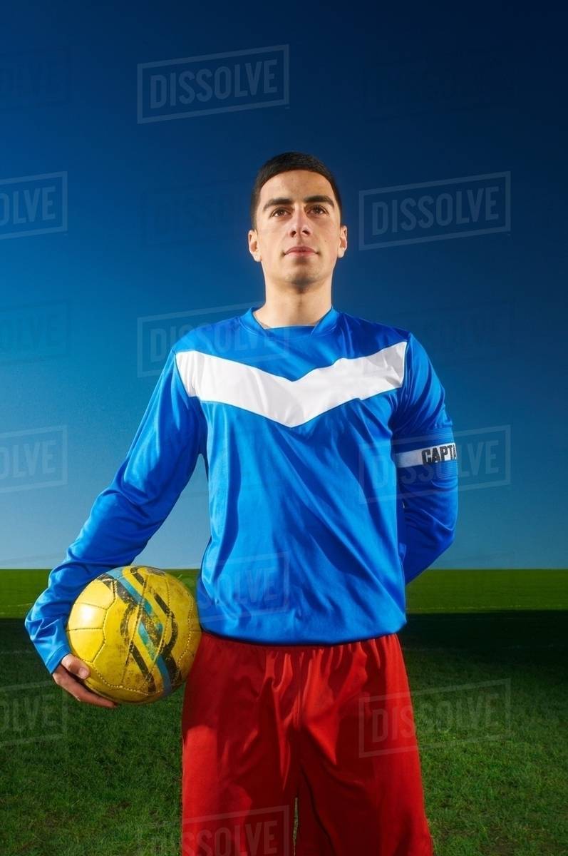Portrait of football team captain holding ball - Stock Photo - Dissolve