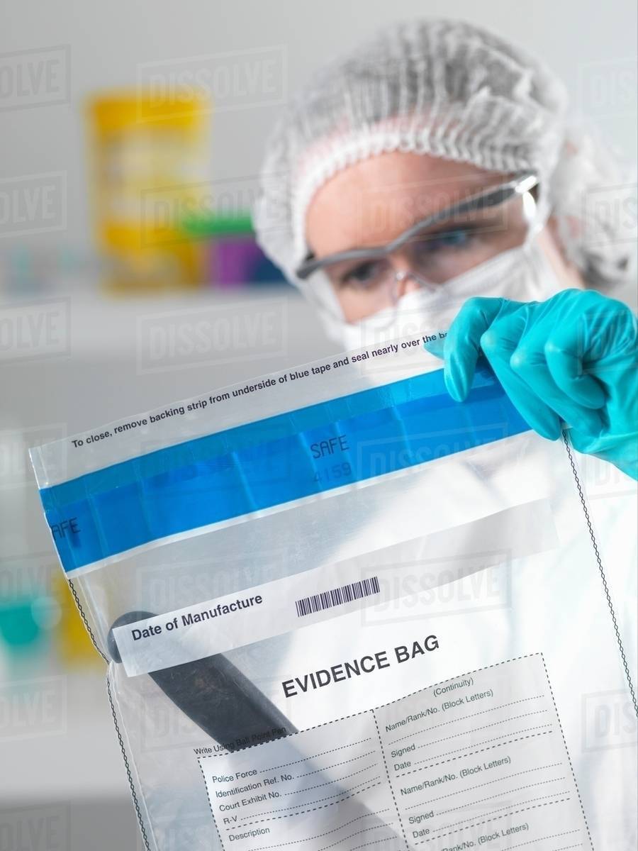 Forensic scientist holding evidence bag from crime scene in laboratory ...