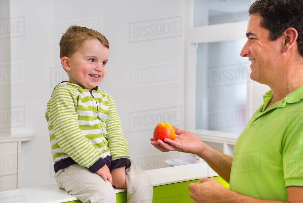Man giving young boy apple - Royalty-free Stock Photo | Dissolve