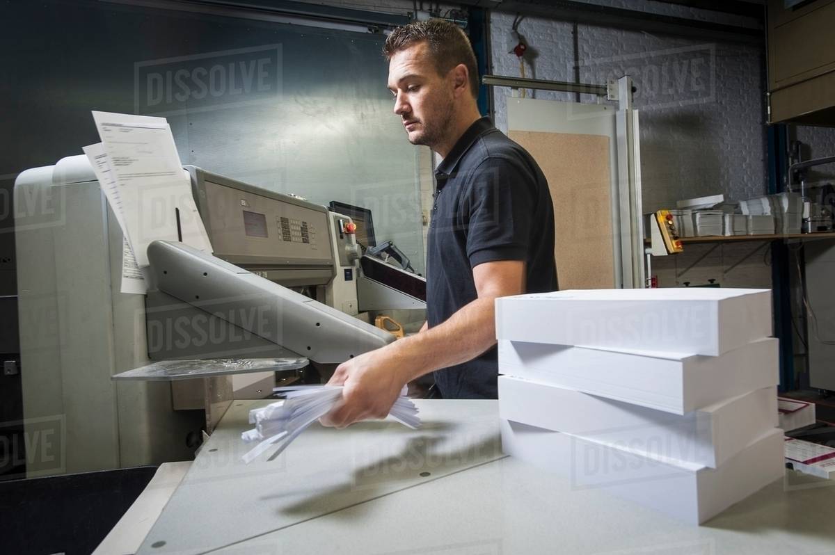 Worker disposing of paper trimmings in print workshop - Stock Photo ...