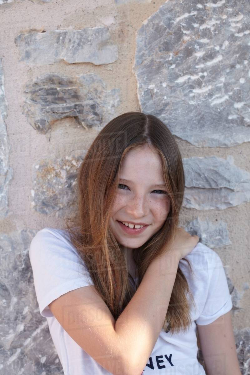 Portrait of shy smiling girl leaning against wall - Royalty-free Stock ...
