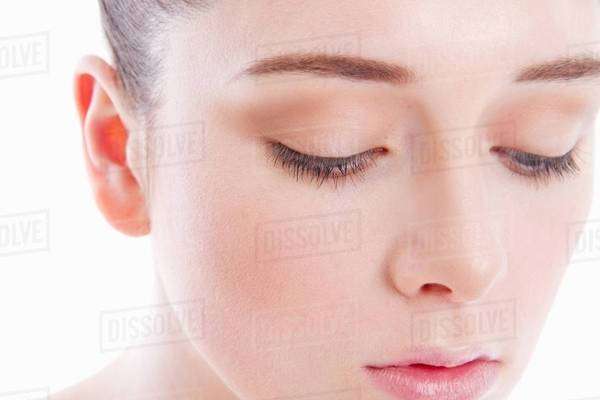 Young woman's face, eyes looking down, close-up - Stock Photo - Dissolve