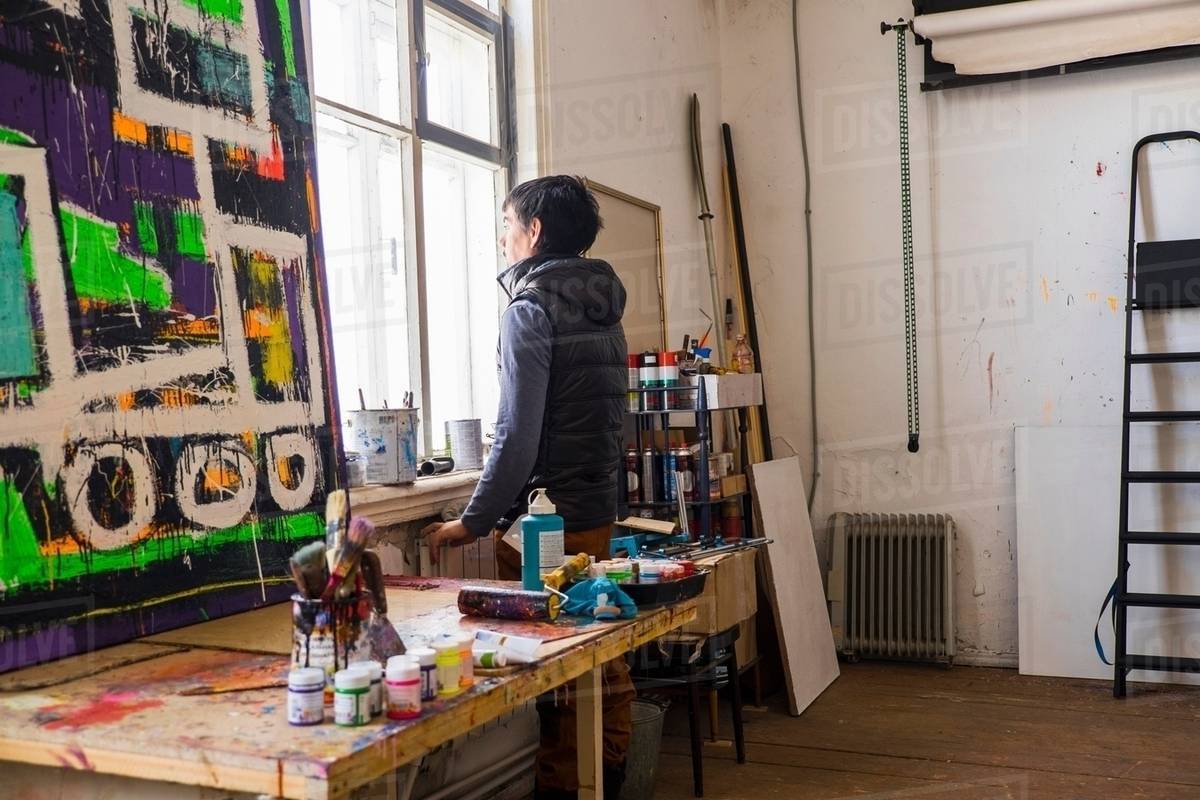 Male artist staring out of studio window - Stock Photo - Dissolve
