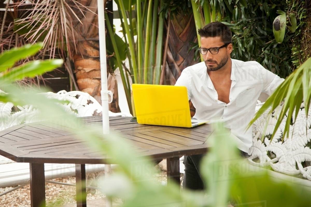 Man using laptop on patio - Royalty-free Stock Photo | Dissolve