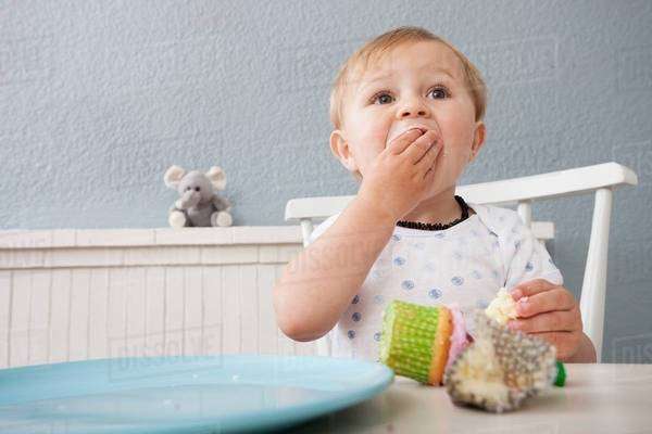 Baby boy eating cupcake - Stock Photo - Dissolve