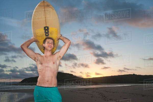Surfer standing on beach carrying surfboard - Royalty-free Stock Photo ...