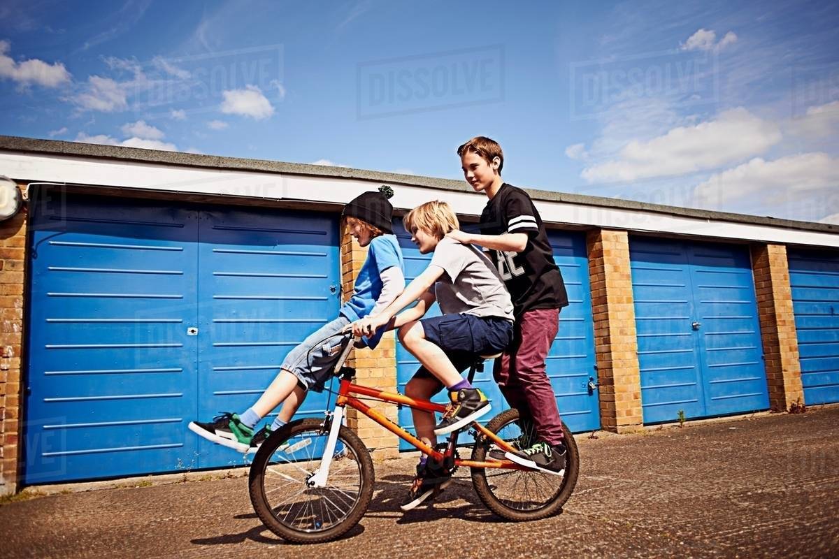 Boy giving two friends a ride on bike - Stock Photo - Dissolve