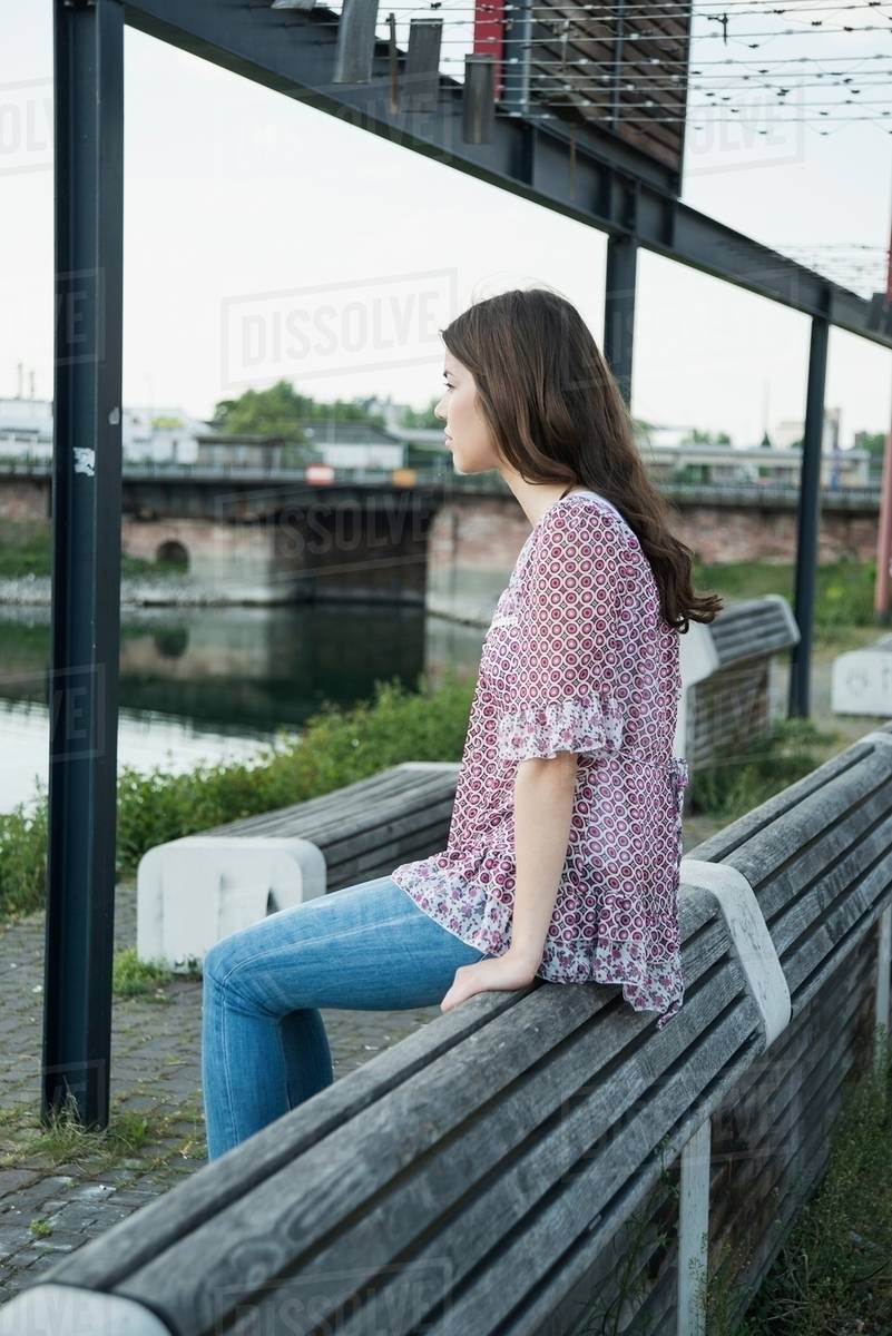 Young woman sitting on bench - Royalty-free Stock Photo | Dissolve