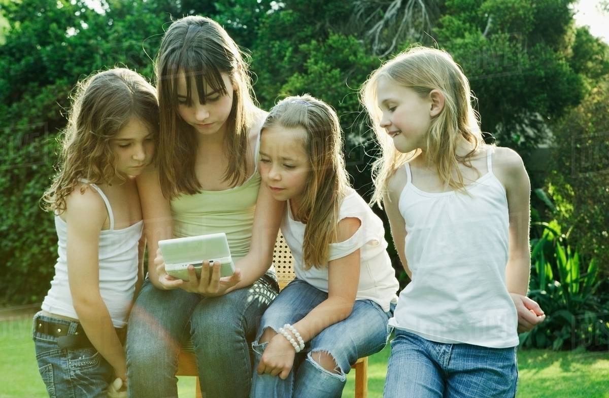 Group of girls playing with Gameboy - Stock Photo - Dissolve