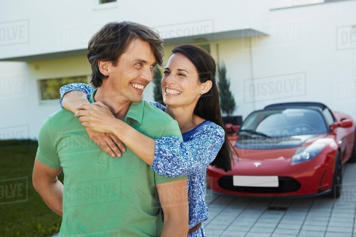 Couple in front of house + electric car - Stock Photo - Dissolve