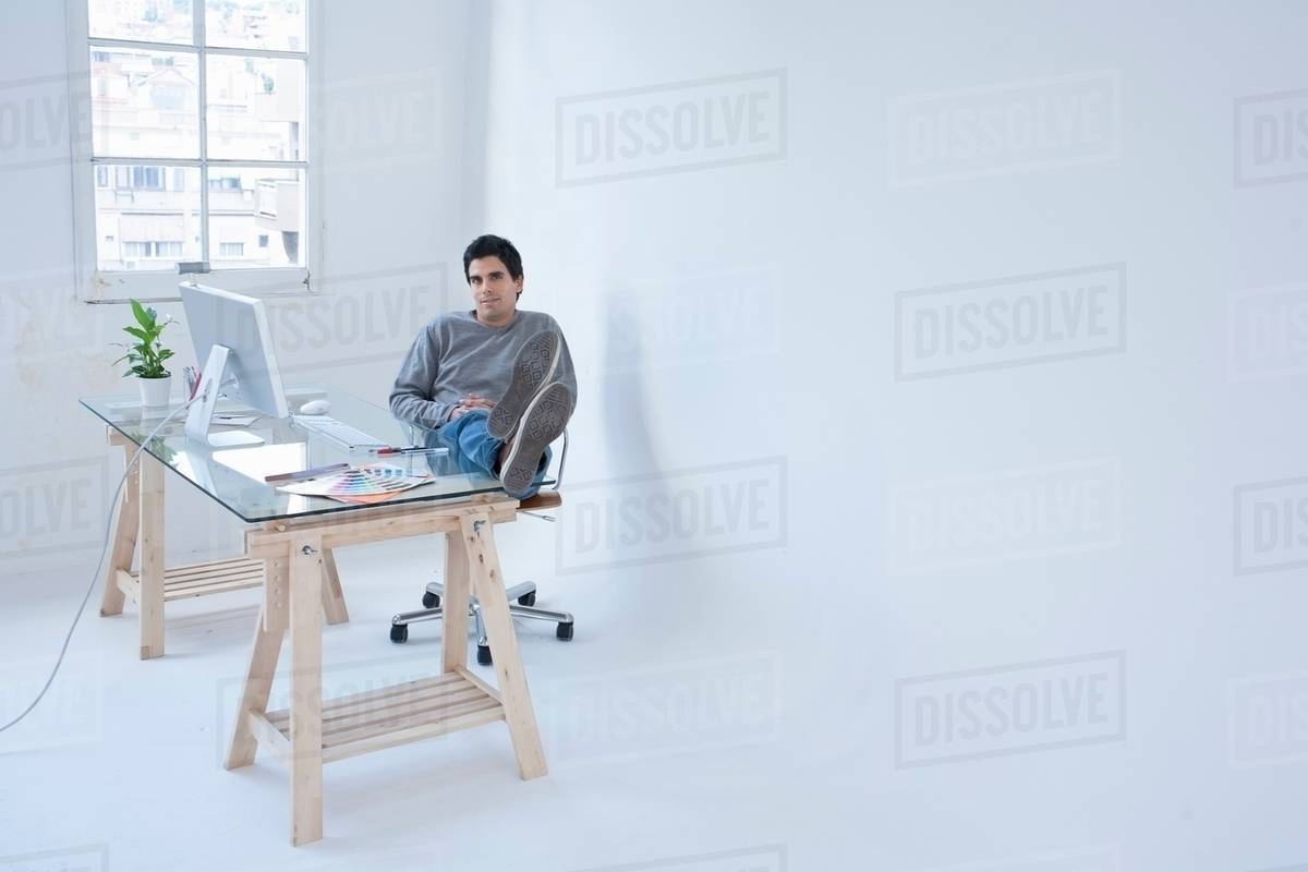 Man sitting at computer with his feet up - Stock Photo - Dissolve
