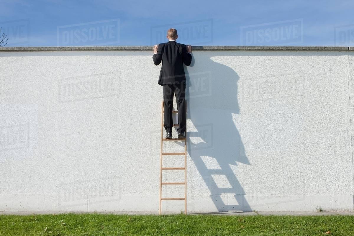 Businessman on ladder looking over wall - Royalty-free Stock Photo ...