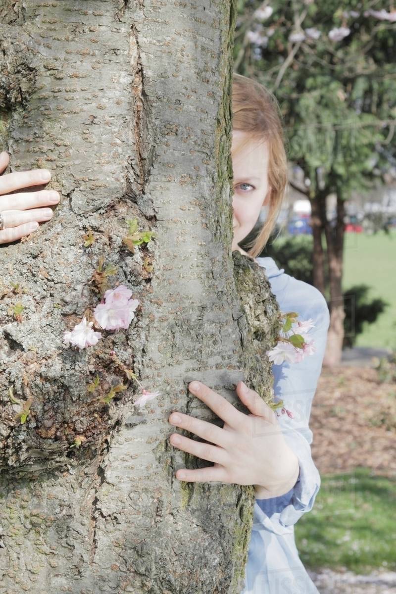 Woman peeking out from behind tree - Royalty-free Stock Photo | Dissolve