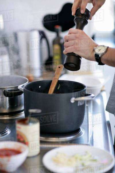Man grinding pepper into pot - Royalty-free Stock Photo | Dissolve