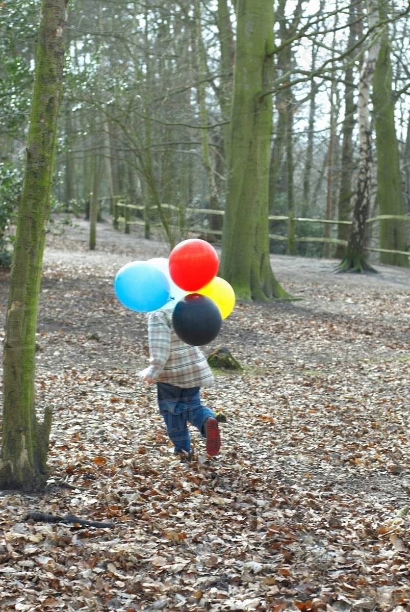 Boy carrying bunch of balloons outdoors - Royalty-free Stock Photo ...