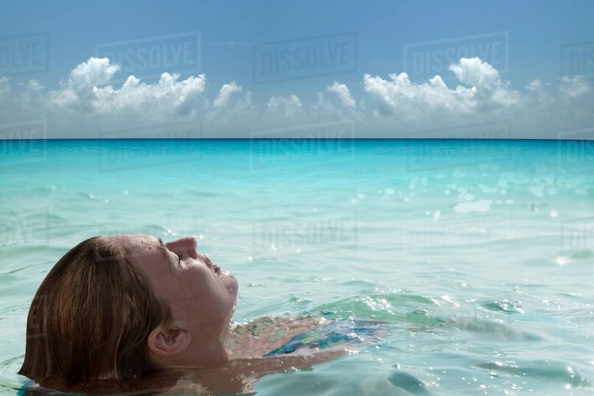 Woman floating in calm sea - Stock Photo - Dissolve