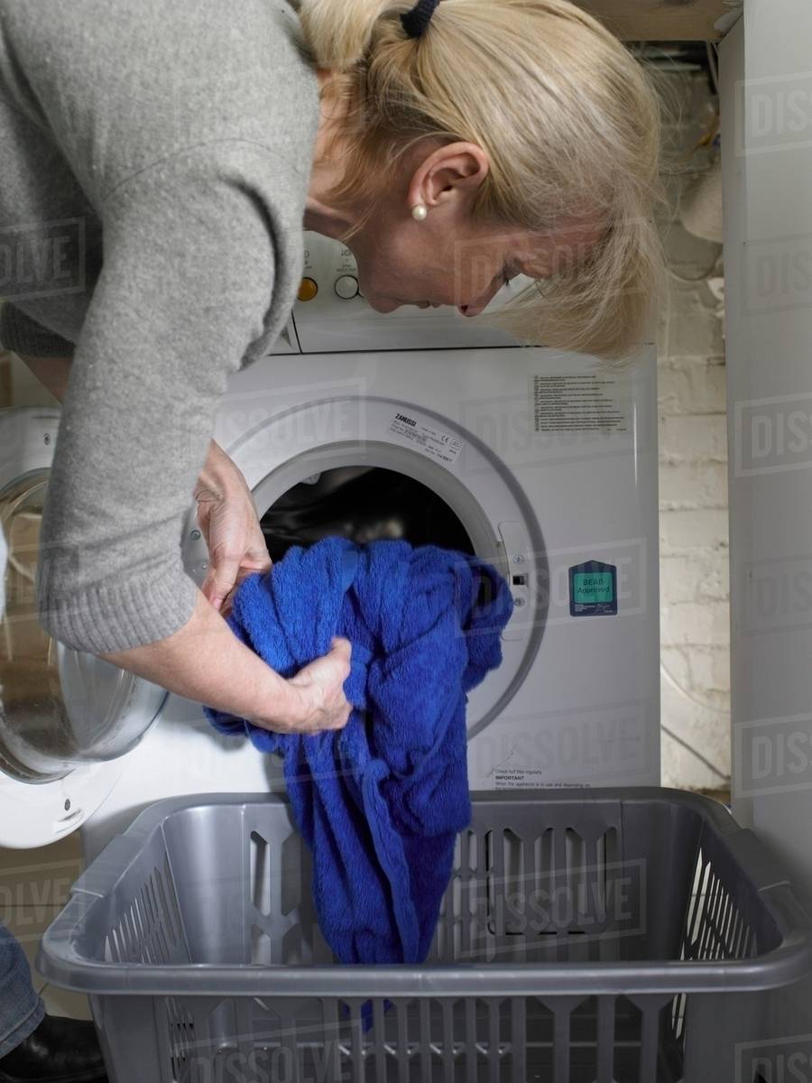 Woman unloading clothes from dryer - Stock Photo - Dissolve