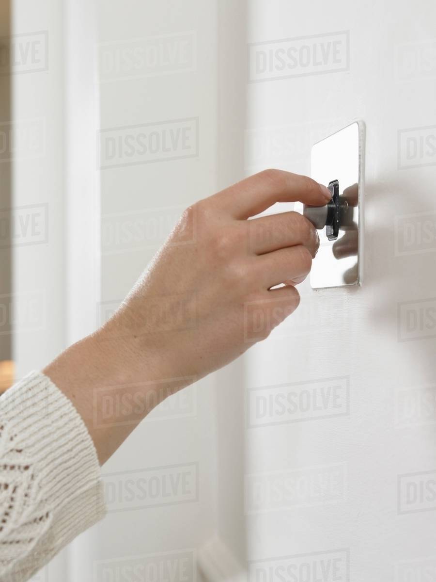 Woman turning on light switch - Royalty-free Stock Photo | Dissolve