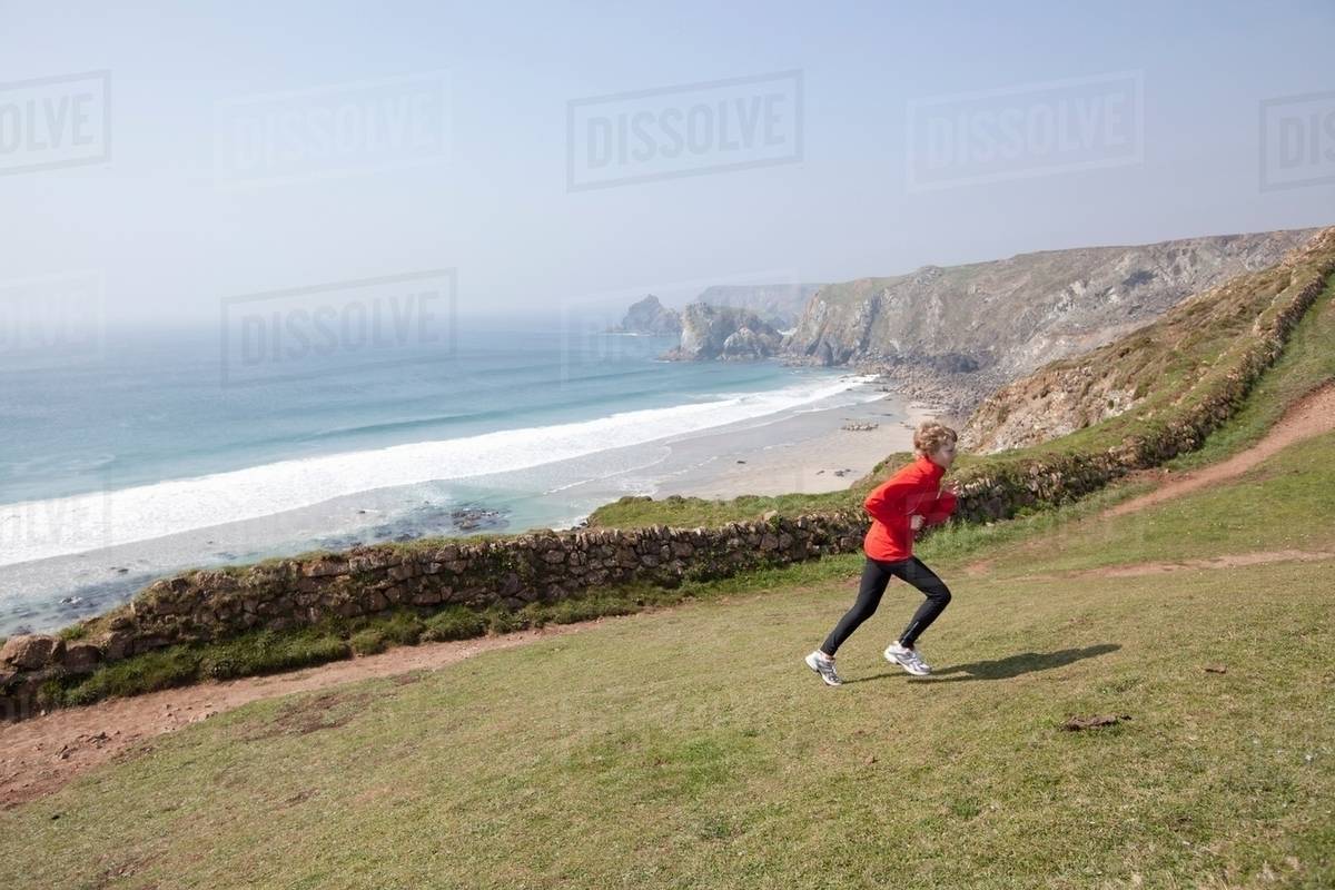 Boy running on cliffs over beach - Royalty-free Stock Photo | Dissolve