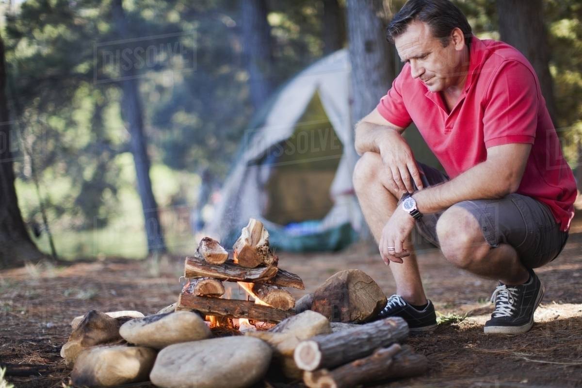 Man starting a fire at campsite - Royalty-free Stock Photo | Dissolve
