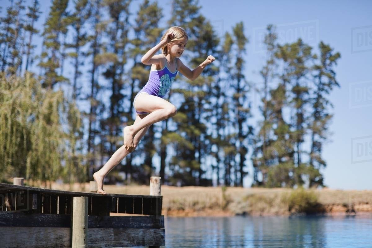 Girl jumping into lake from jetty - Royalty-free Stock Photo | Dissolve