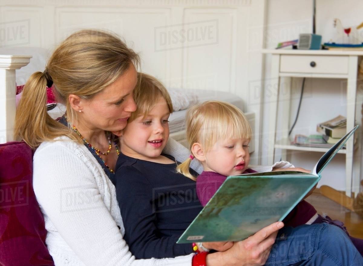Mother reading to children in bedroom - Stock Photo - Dissolve