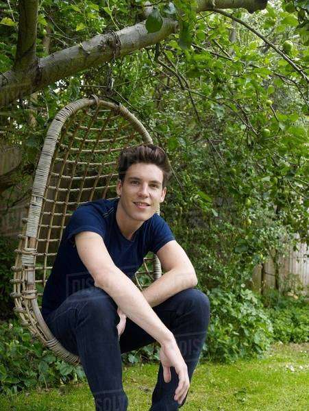 Man sitting in chair swing outdoors - Royalty-free Stock Photo | Dissolve