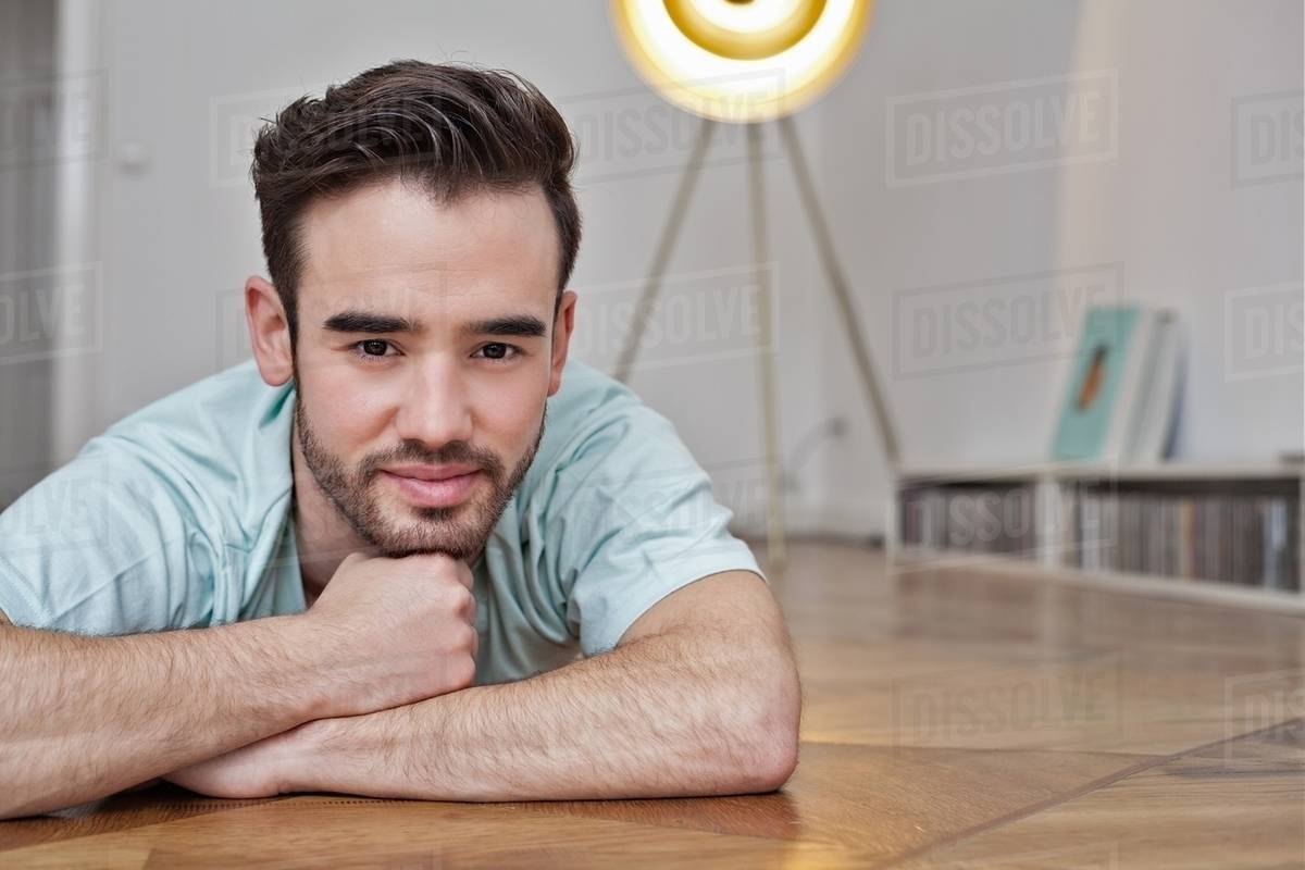 Smiling man laying on floor - Stock Photo - Dissolve