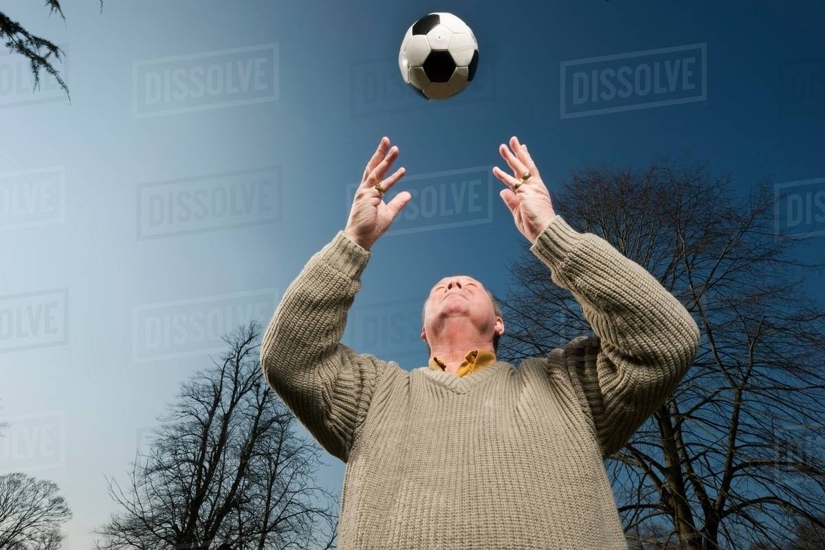 Older man playing with soccer ball - Stock Photo - Dissolve