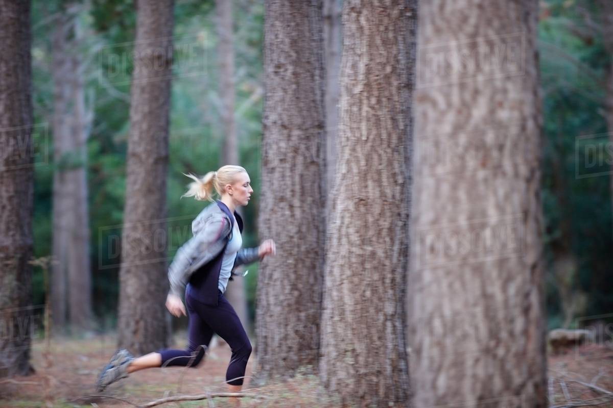 Woman running in forest - Stock Photo - Dissolve
