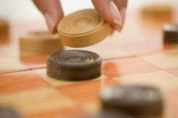 Close up of woman playing checkers - Stock Photo - Dissolve
