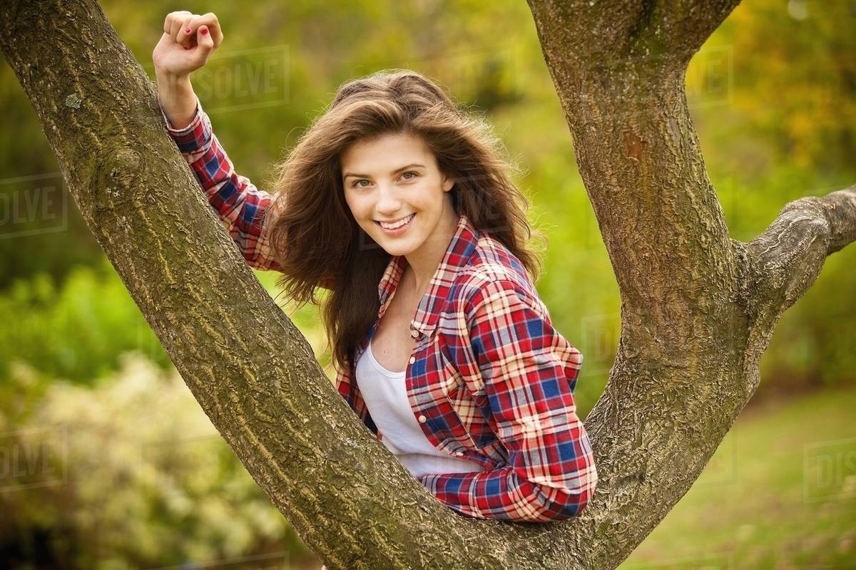 Teenage girl climbing tree in park - Royalty-free Stock Photo | Dissolve