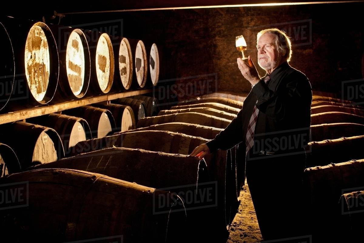 Worker testing whisky in distillery - Royalty-free Stock Photo | Dissolve