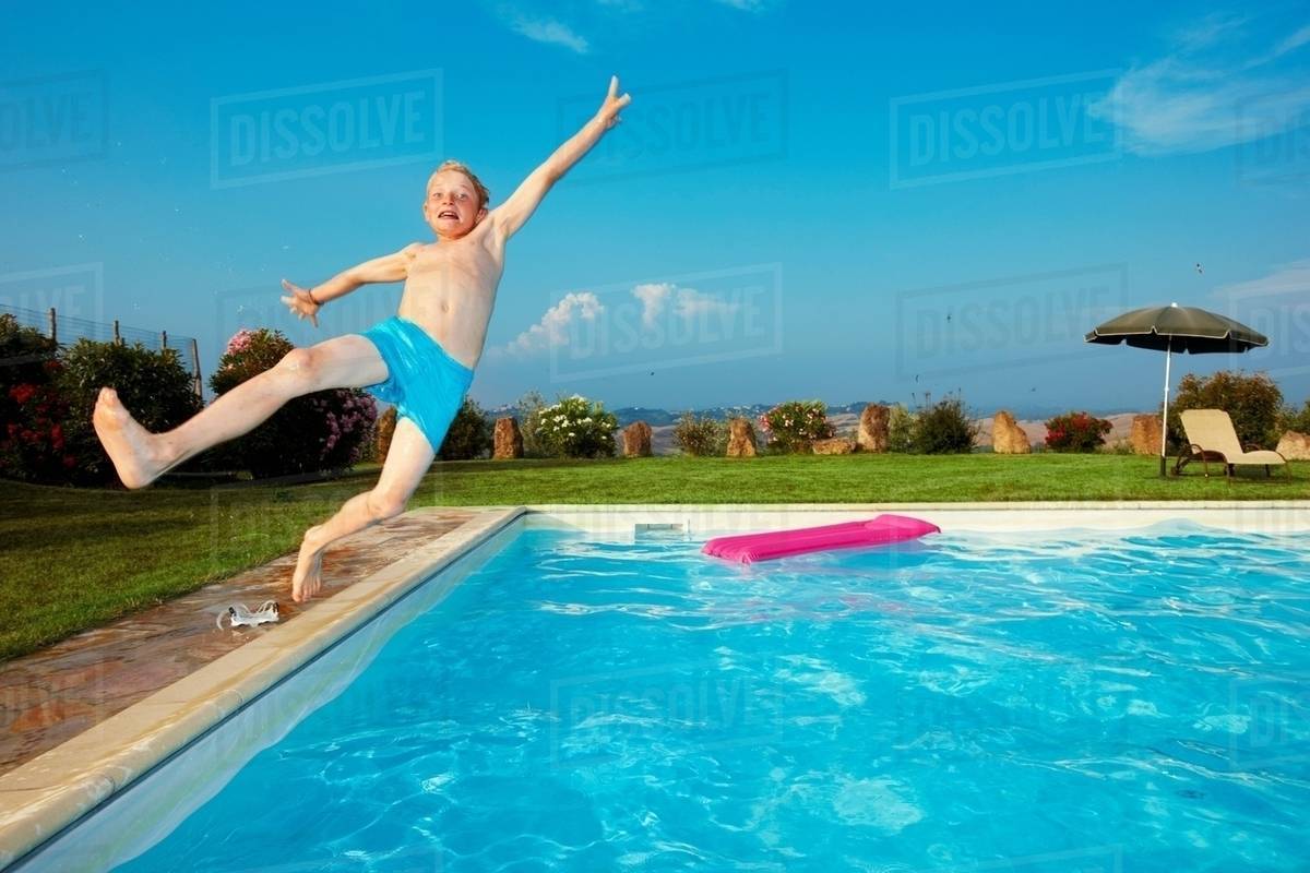 Boy jumping into swimming pool - Stock Photo - Dissolve