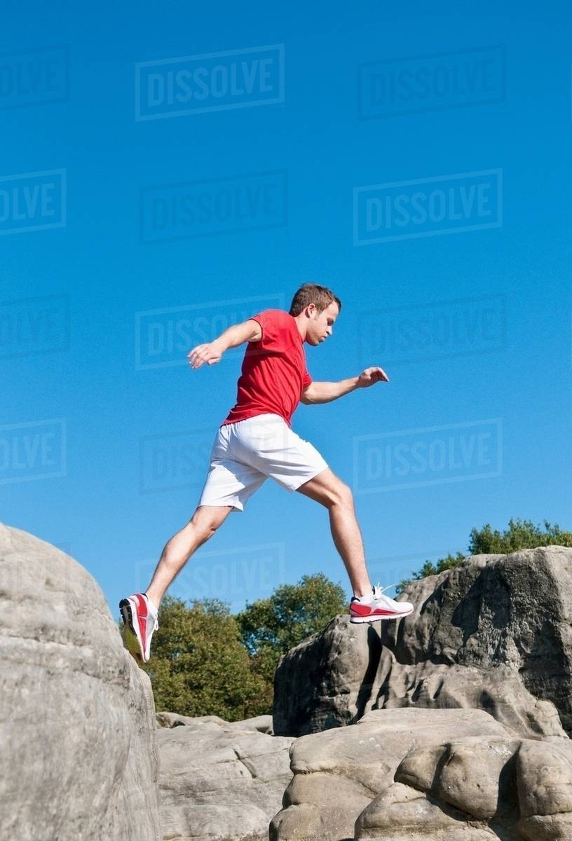 Rock climber jumping between rocks - Royalty-free Stock Photo | Dissolve