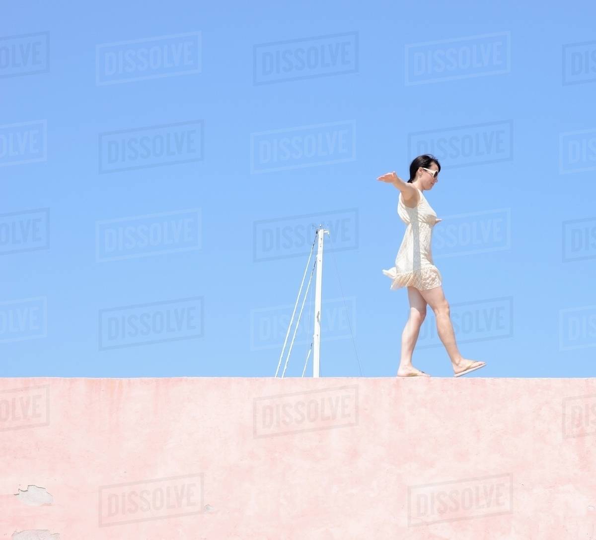 Woman balancing on wall - Royalty-free Stock Photo | Dissolve