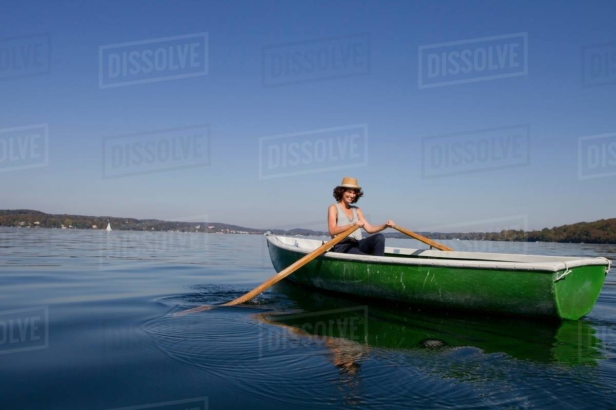 Woman rowing boat in still lake - Royalty-free Stock Photo | Dissolve