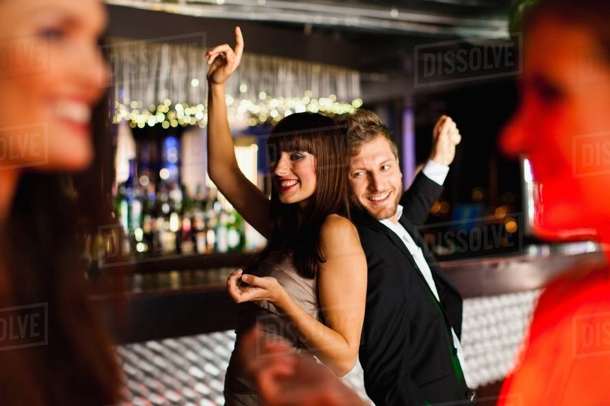 Smiling friends dancing in bar - Stock Photo - Dissolve