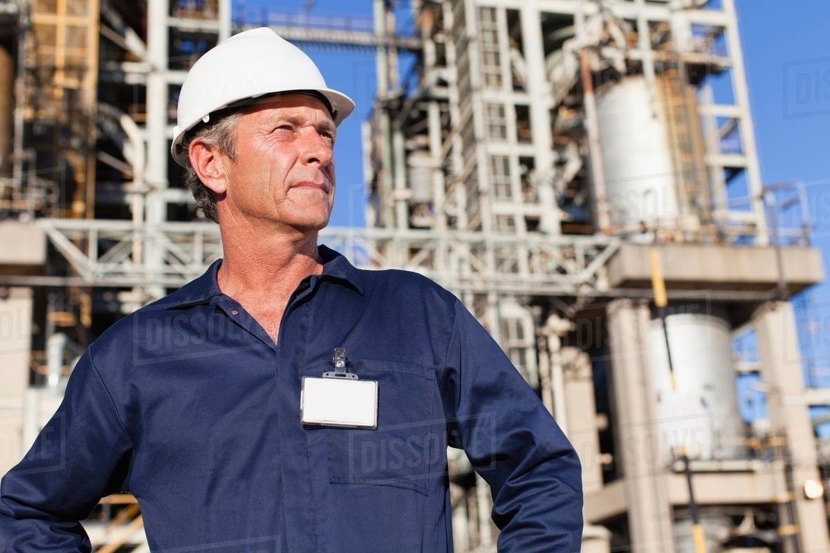Worker standing at oil refinery - Stock Photo - Dissolve