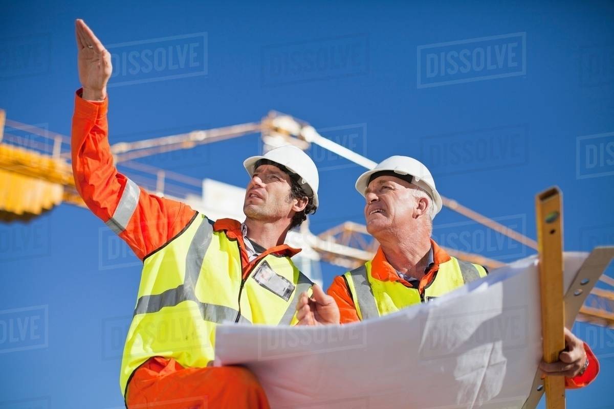 Workers reading blueprints on site - Royalty-free Stock Photo | Dissolve