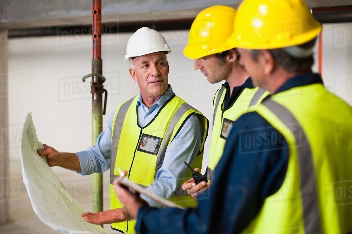 Workers reading blueprints on site - Stock Photo - Dissolve