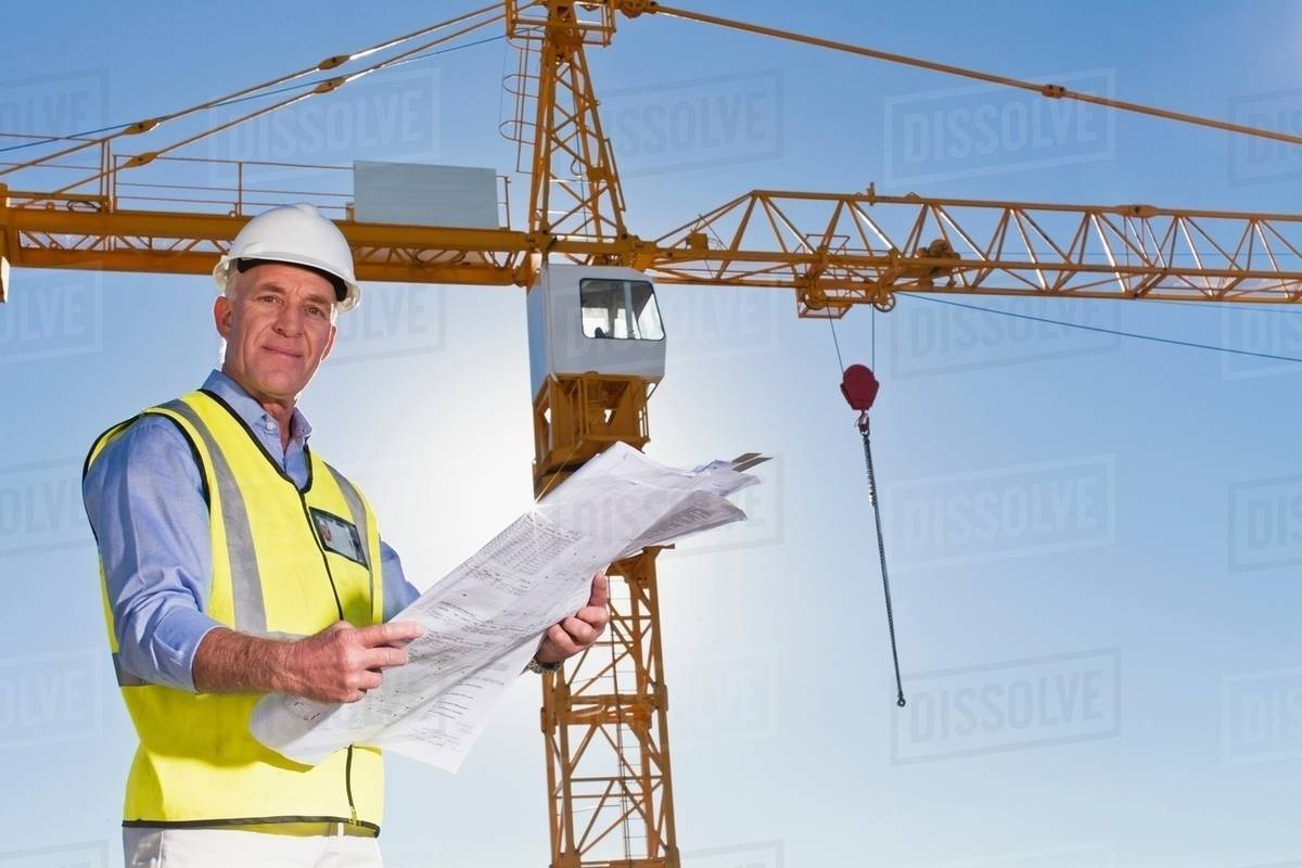 Worker reading blueprints on site - Royalty-free Stock Photo | Dissolve