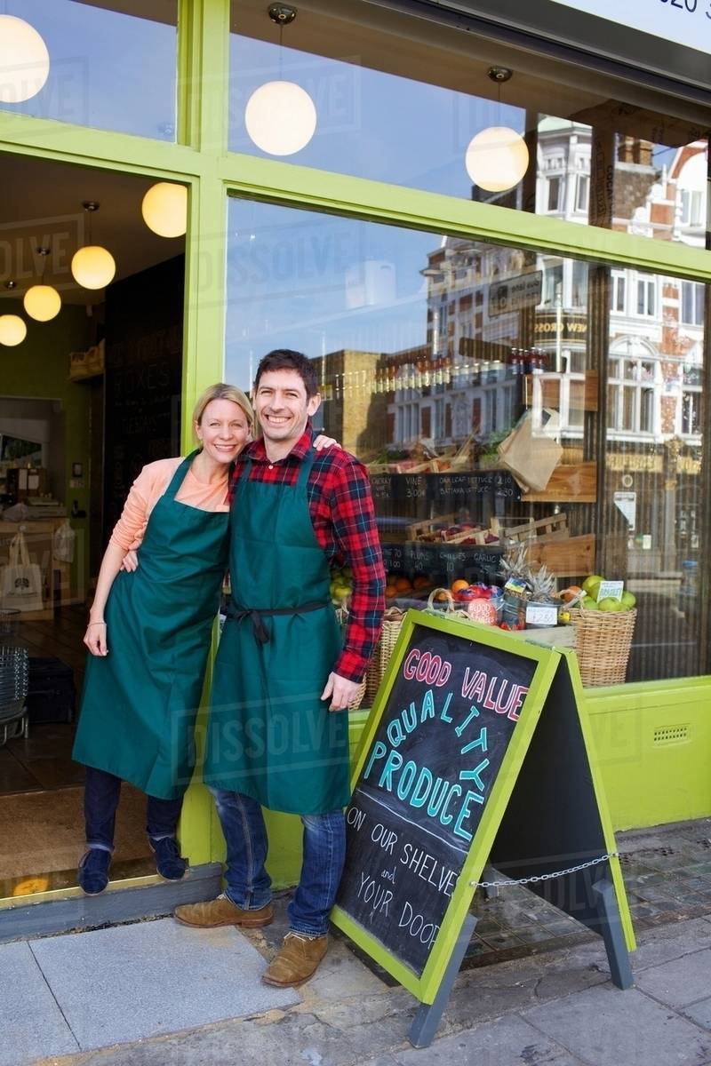 Smiling grocers standing outside store - Stock Photo - Dissolve