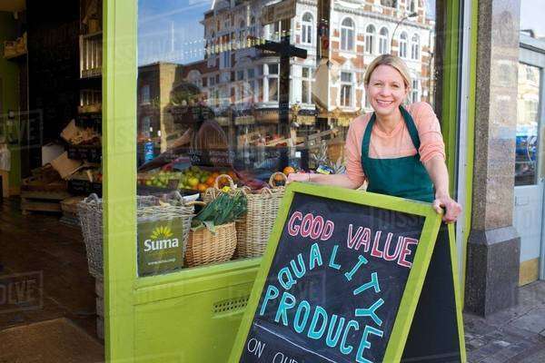 Smiling grocer standing outside store - Royalty-free Stock Photo | Dissolve