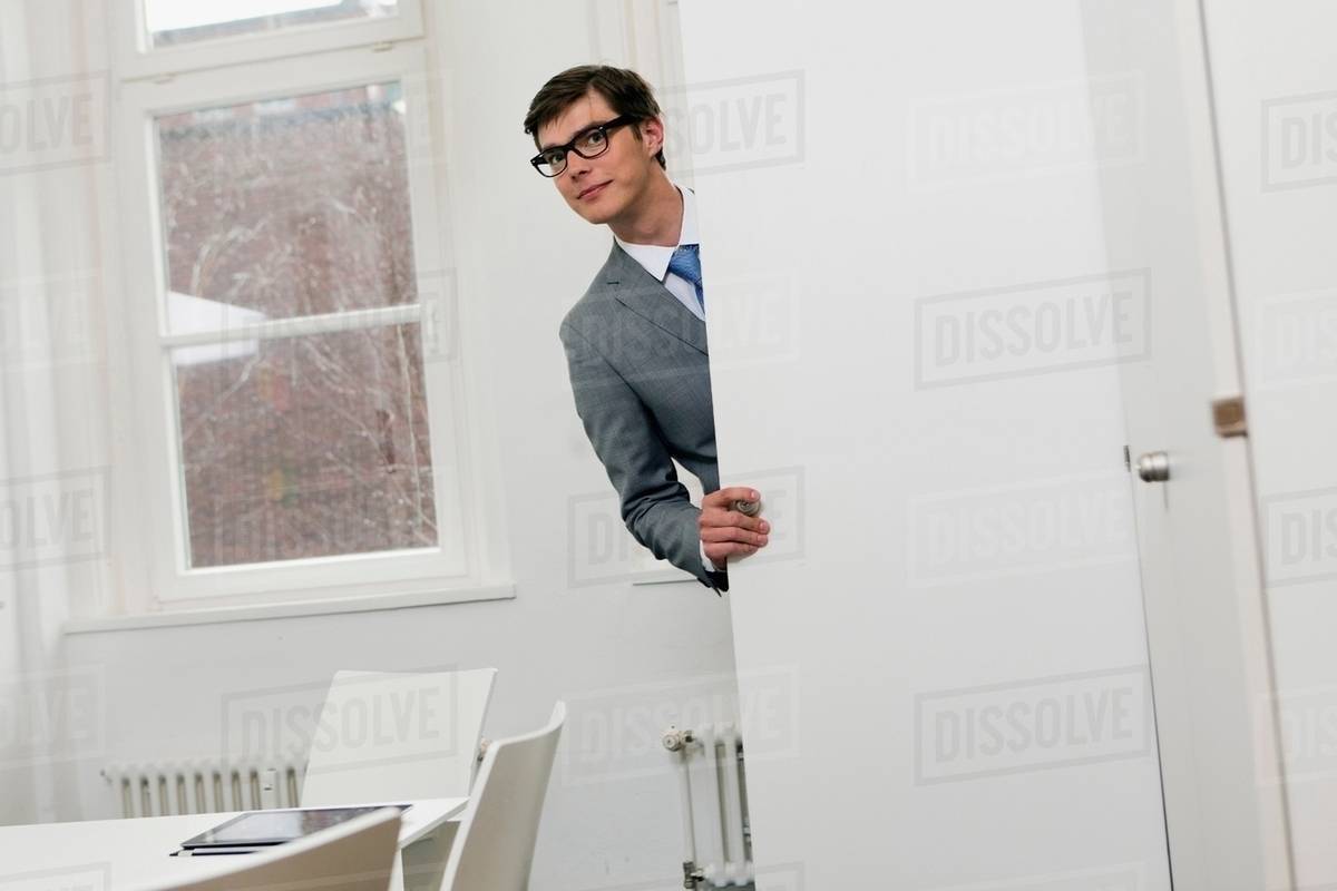 Businessman peering around door - Stock Photo - Dissolve