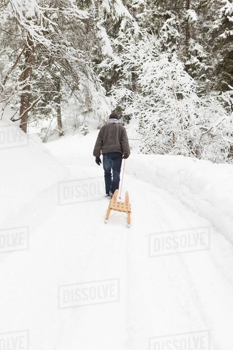 Man pulling sled in snowy field - Royalty-free Stock Photo | Dissolve