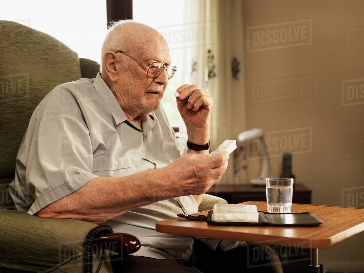 Older man taking medication in armchair - Royalty-free Stock Photo ...