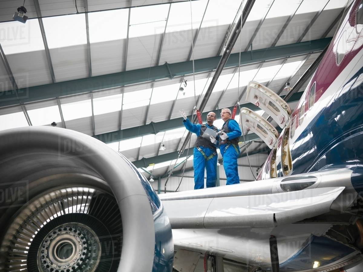 Aircraft engineers working on wing of 737 jet airplane in airport ...